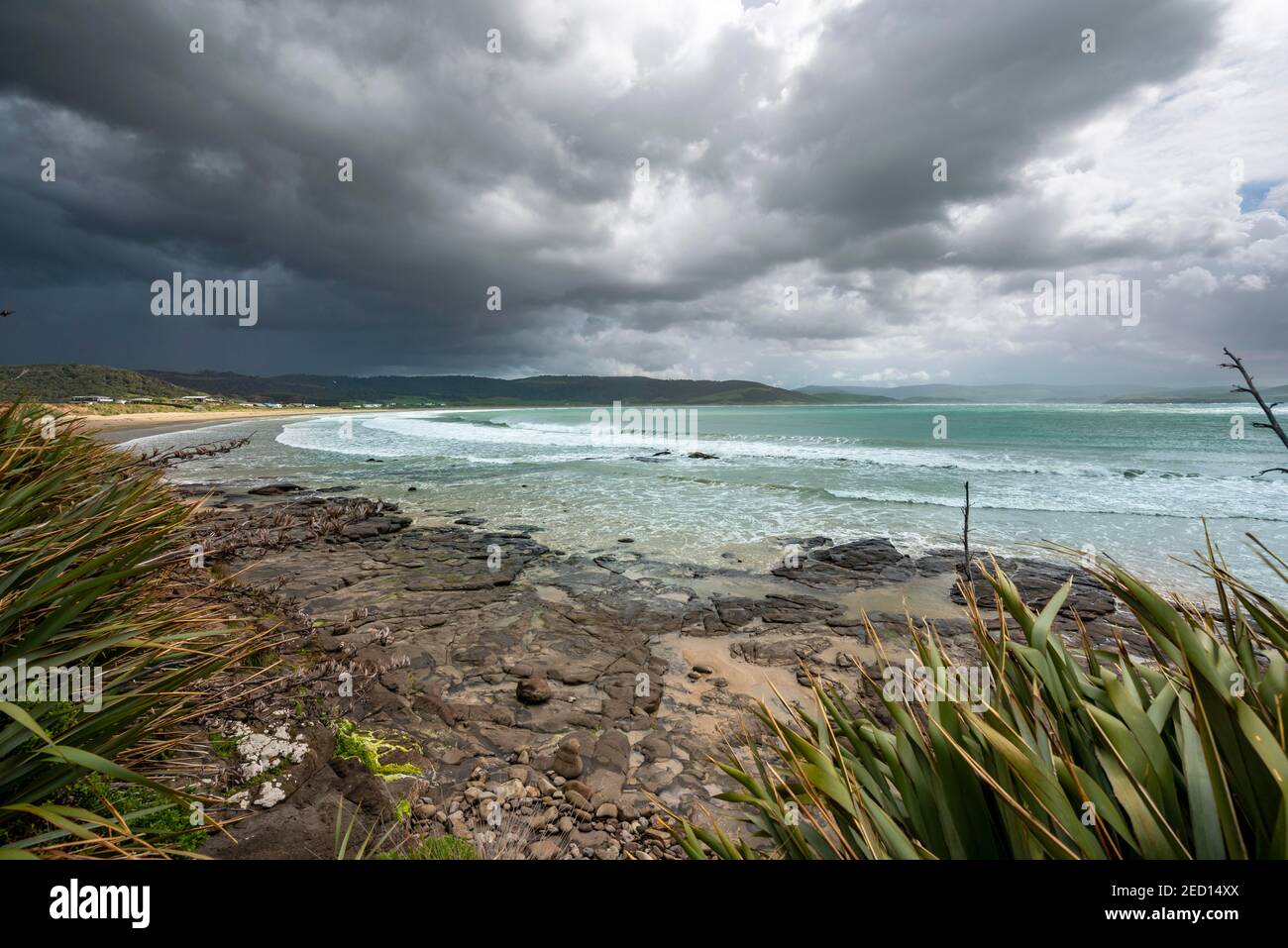 View of sandy beach and sea at Curio Bay, dramatic cloudy sky, Curio ...