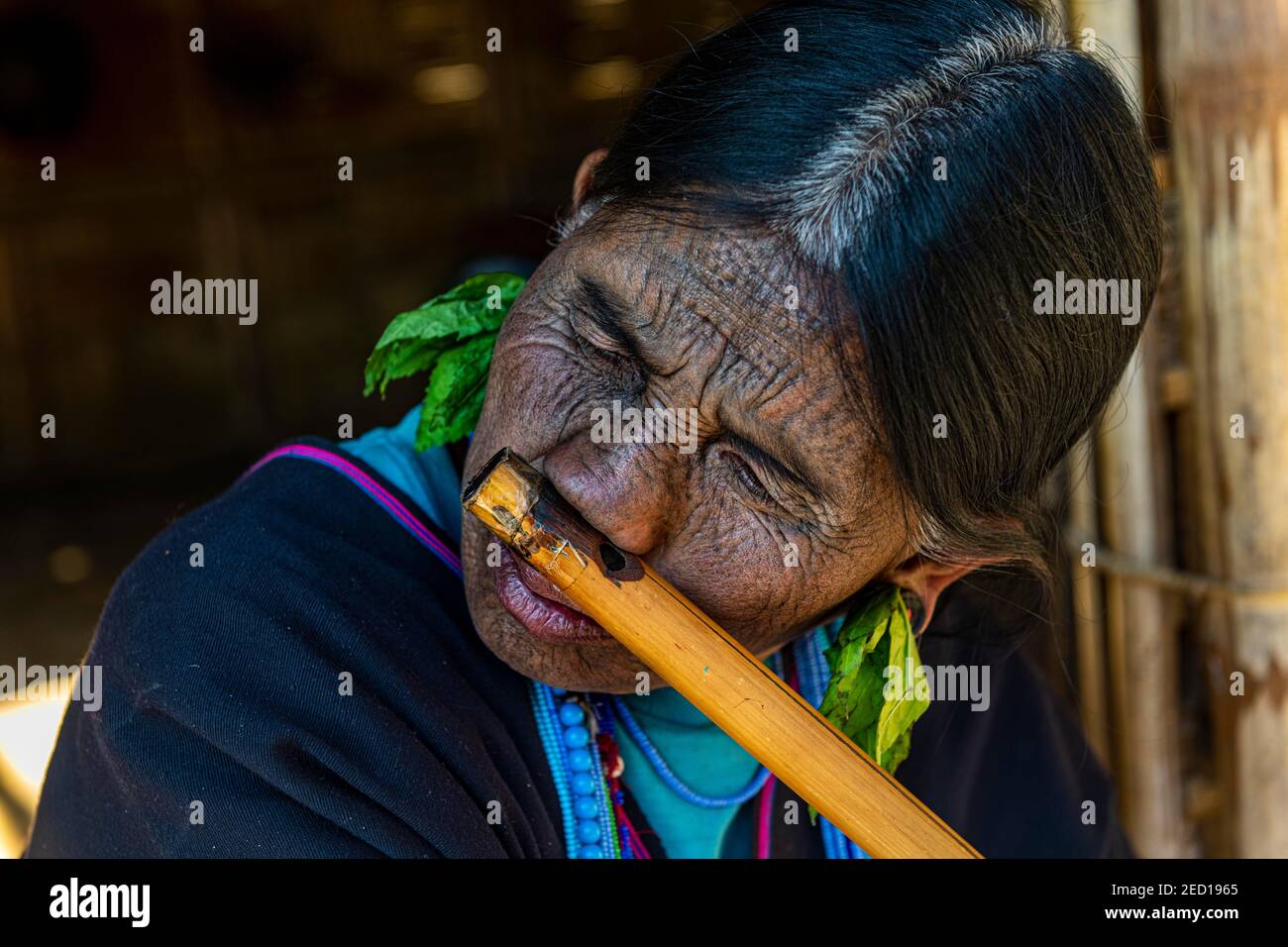 Chin woman with spiderweb tattoo blowing a flute with her nose ...