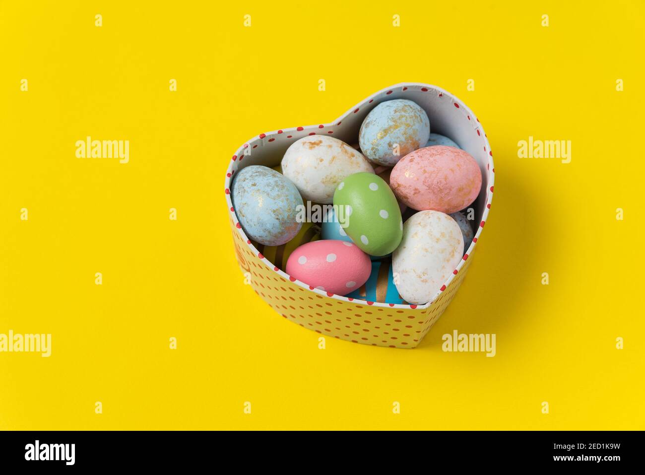 Heart shaped box with colorful Easter eggs on bright yellow background ...