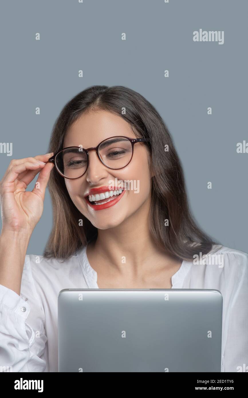 Laughing woman with laptop correcting glasses Stock Photo - Alamy