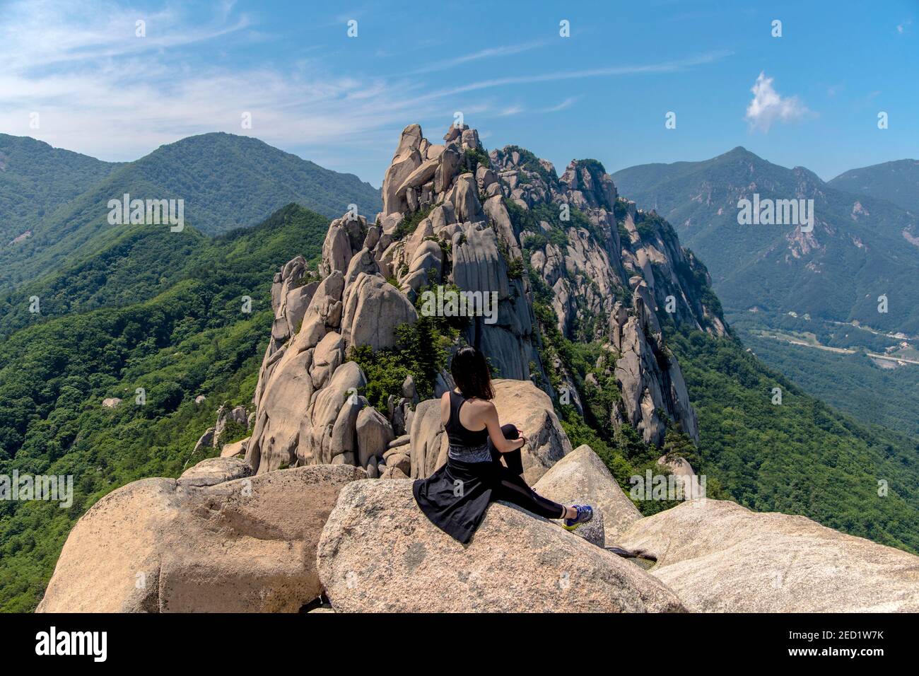 Back view of faceless female hiker sitting on rock of mountain ridge ...
