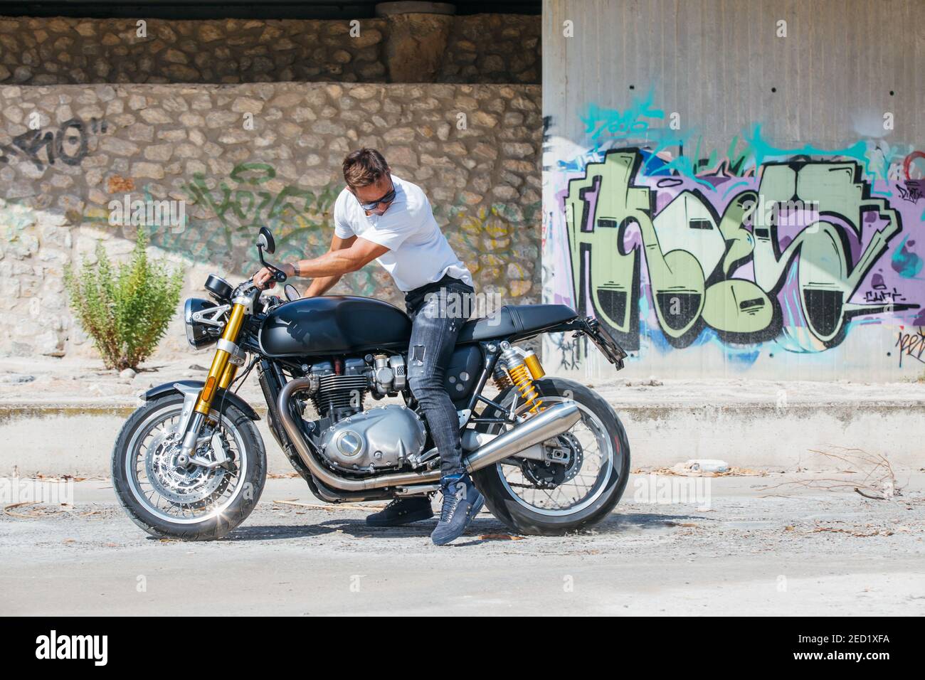 Stylish male biker sitting on modern motorcycle in urban area and ...