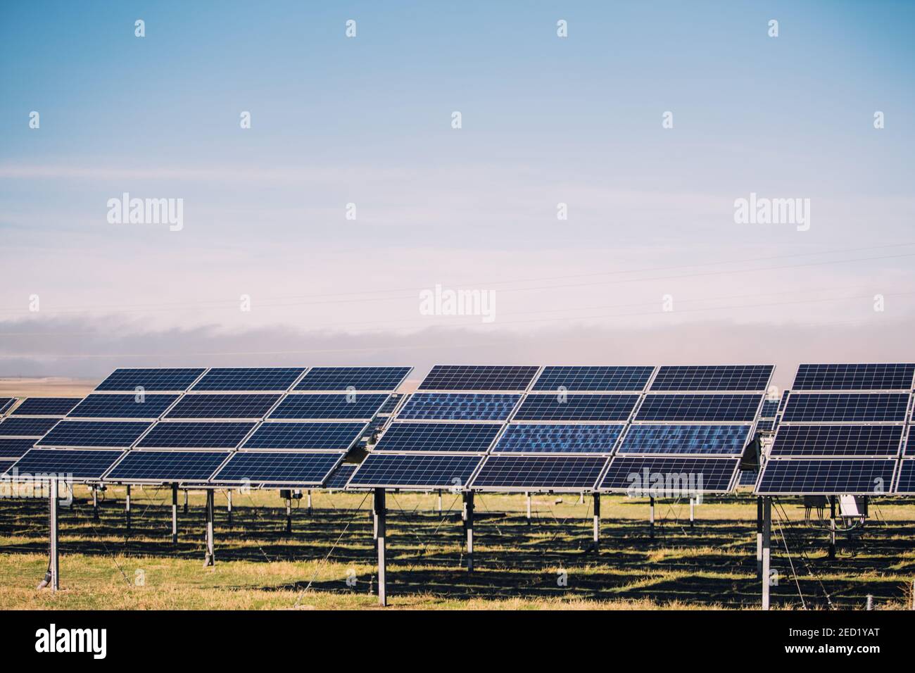 Modern solar panels installed in field against cloudy sky in ...
