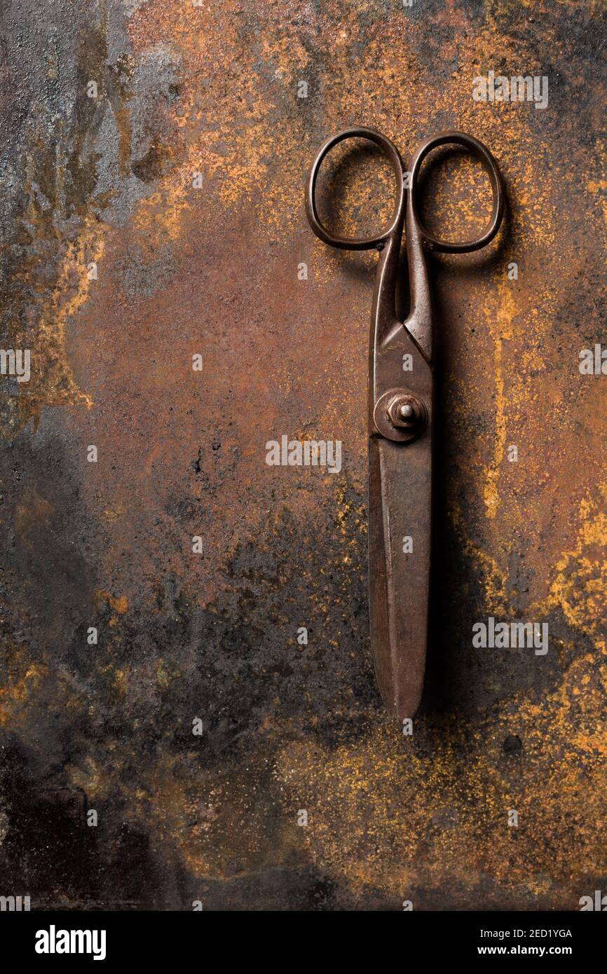 Top view of old metal scissors placed on dark table with rusty surface ...