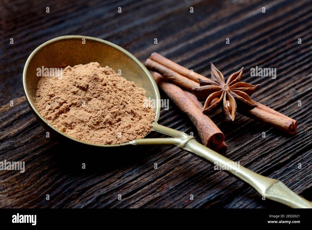 Cinnamonpowder ( Cinnamomum spec.) in brass ladle and star anise sticks ...