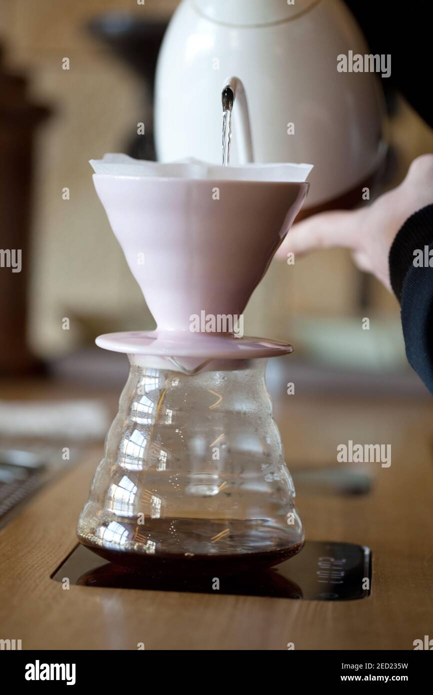 pouring water from kettle into glass pour over on scales closeup ...