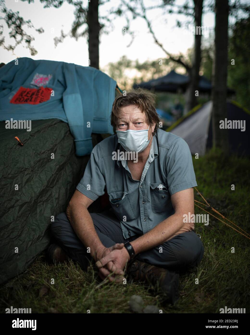 A male activist from Extinction Rebellion sits outside his tent at a ...