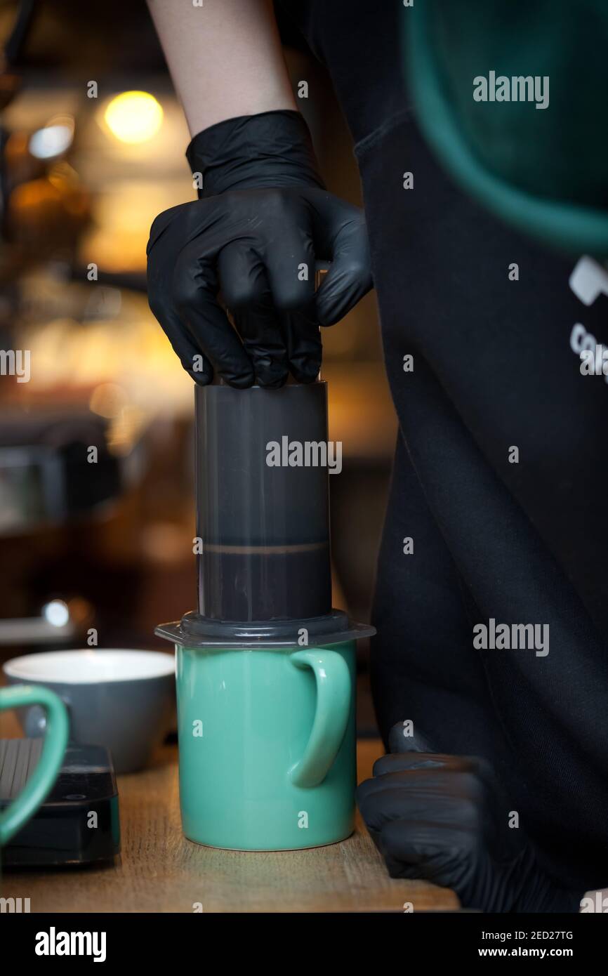 barista hands pressing aeropress into cup, closeup of coffee brewing ...