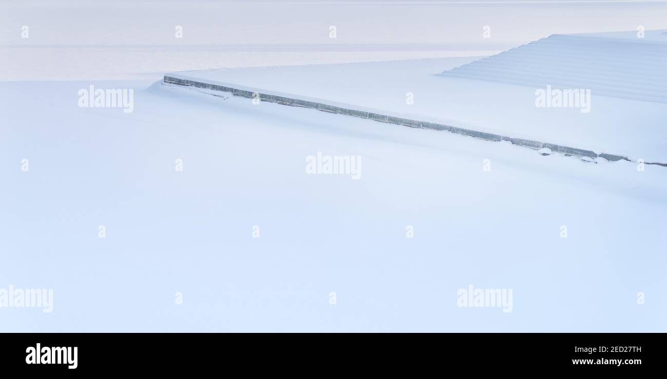 Snow-covered embankment, granite steps and ice surface. Abstract winter ...