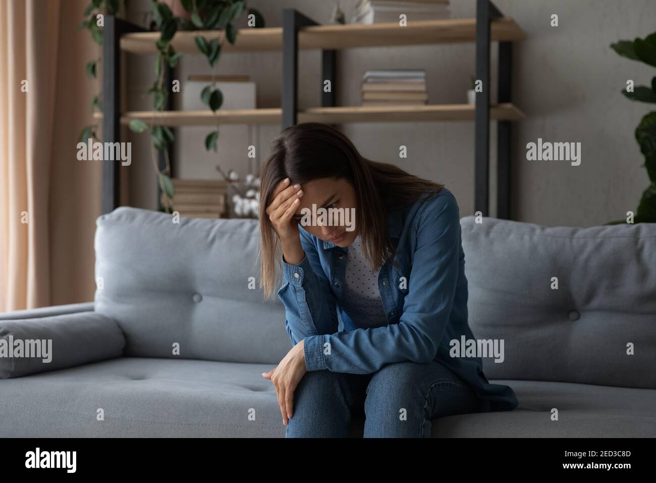 Stressed female sit on couch alone look down having problem Stock Photo ...