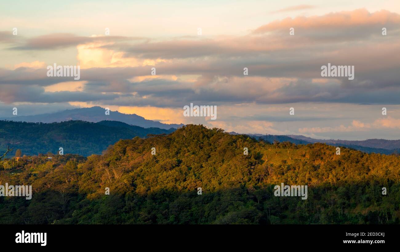 A mesmerizing view of forested mountains under a cloudy sunset sky ...