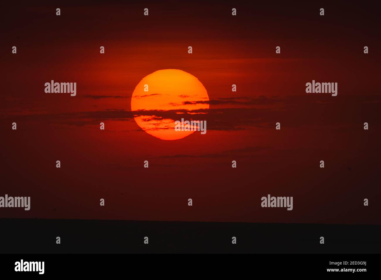 The breathtaking scenery of round orange sunset behind clouds over Lake ...