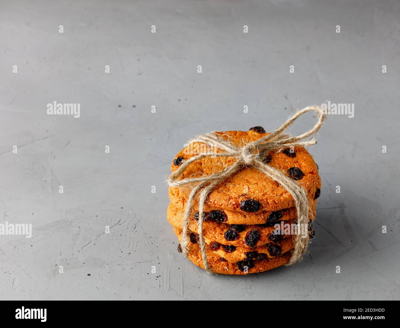 A stack of homemade oatmeal raisin cookies tied in string on a gray ...