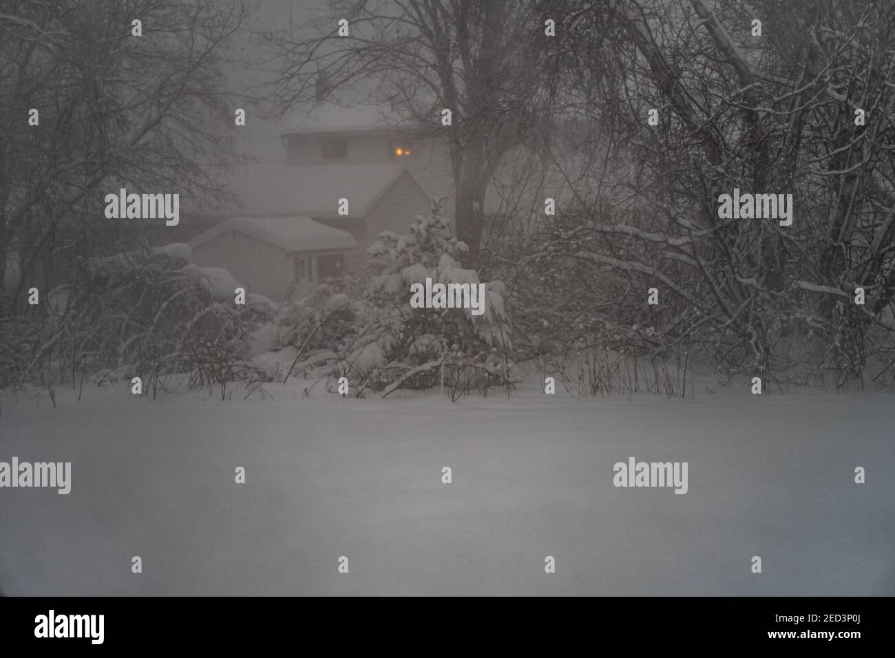 a light in a window during a dark evening winter snow storm Stock Photo ...
