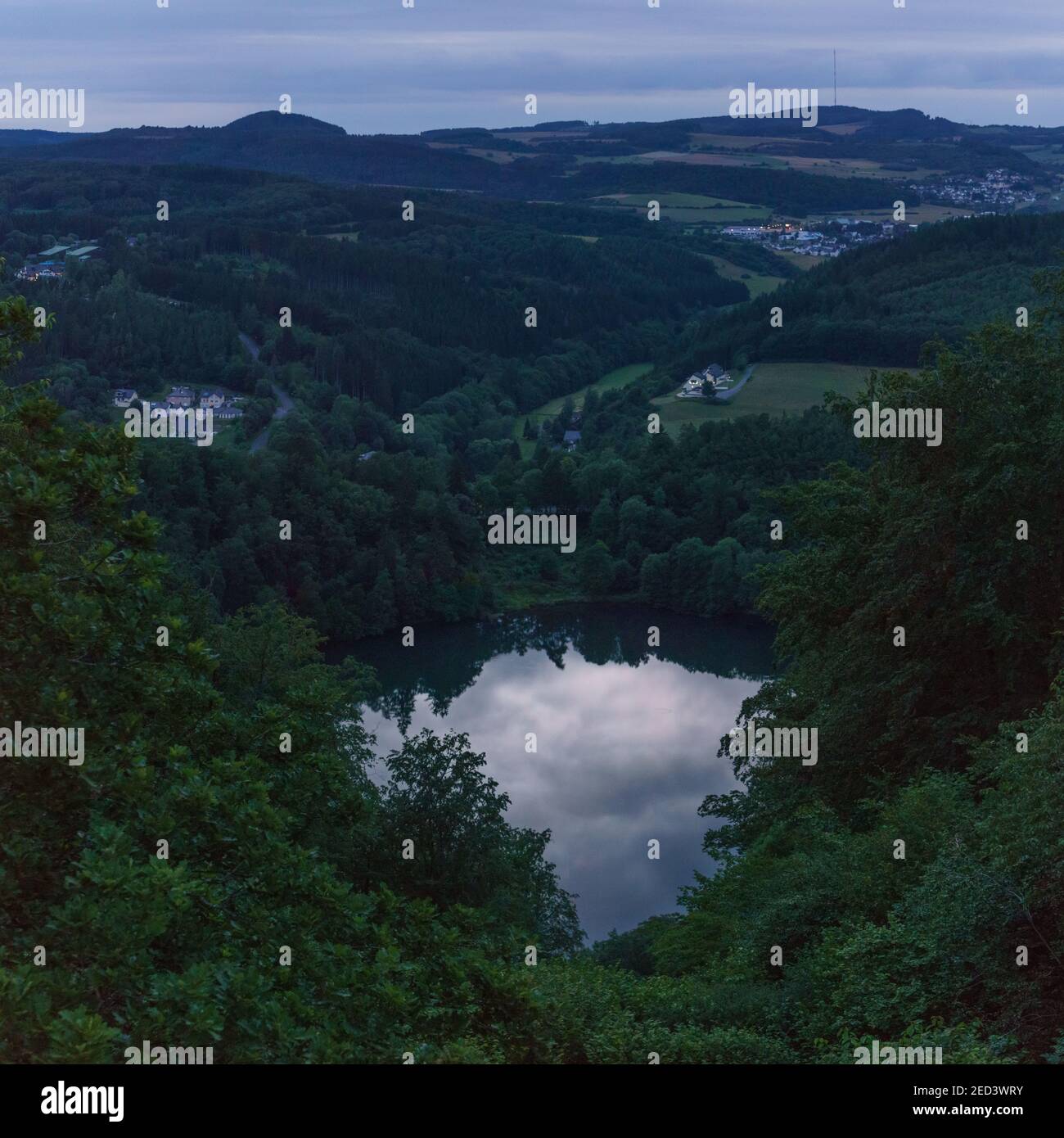 Detail of Gemuenden Maar with building surrounded by forest and city of ...