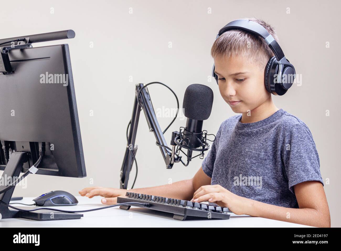 Teenage boy talks looking to computer monitor screen. Kid wearing ...