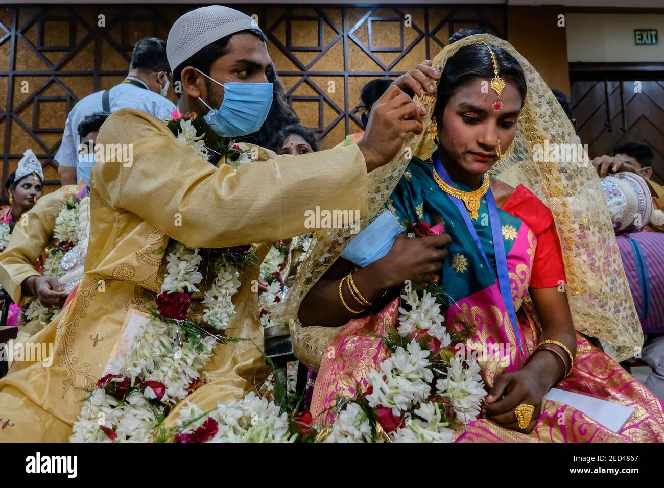 A groom fixing the traditional veil of his bride during the mass ...