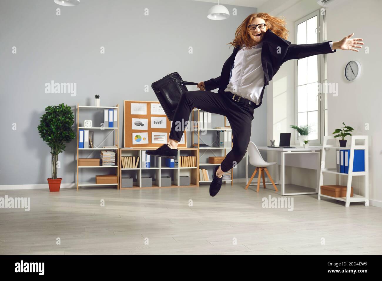Funny office worker is happy that workday is over and is jumping high ...