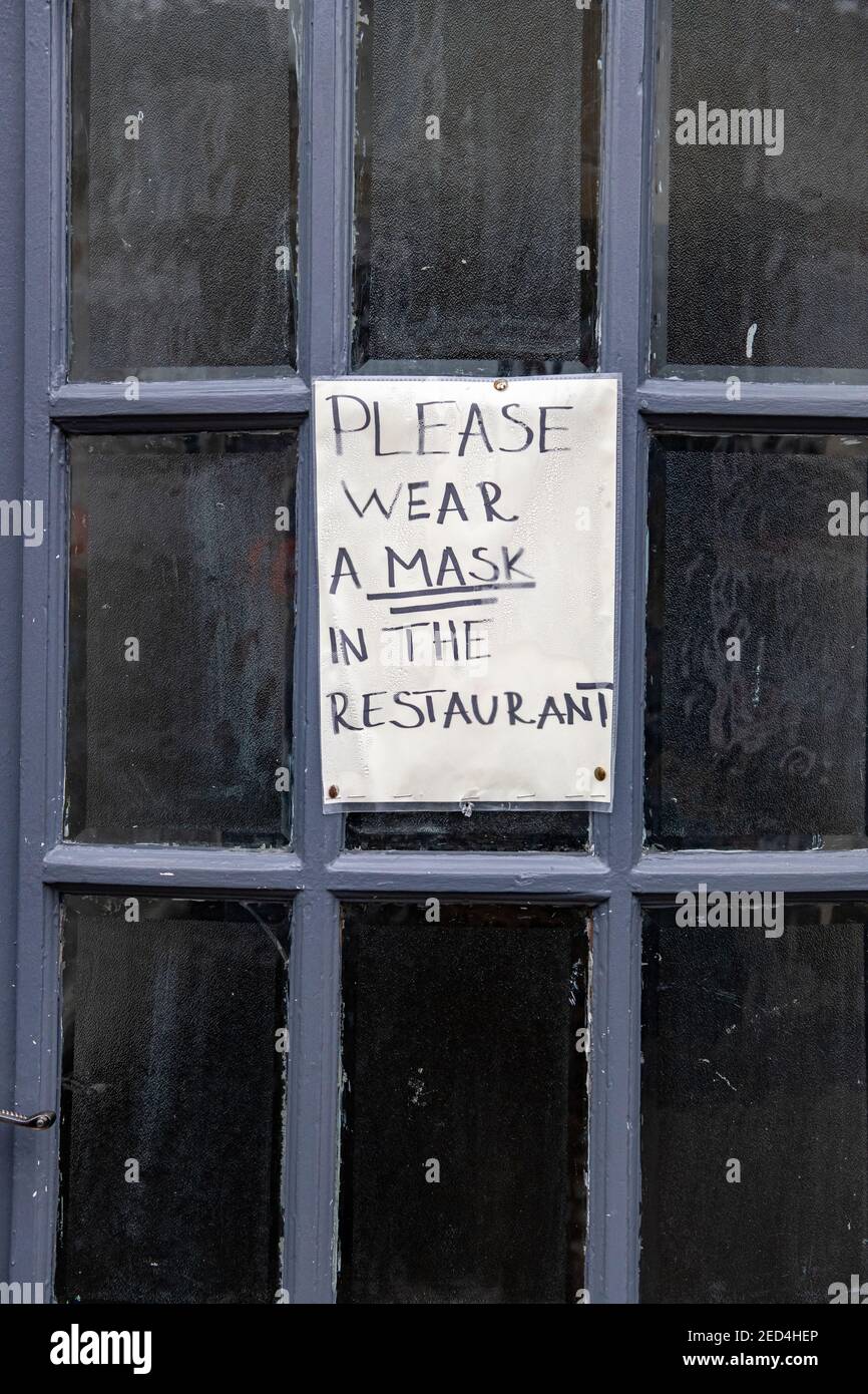 A handwritten sign asks that patrons "Please wear a mask in the ...