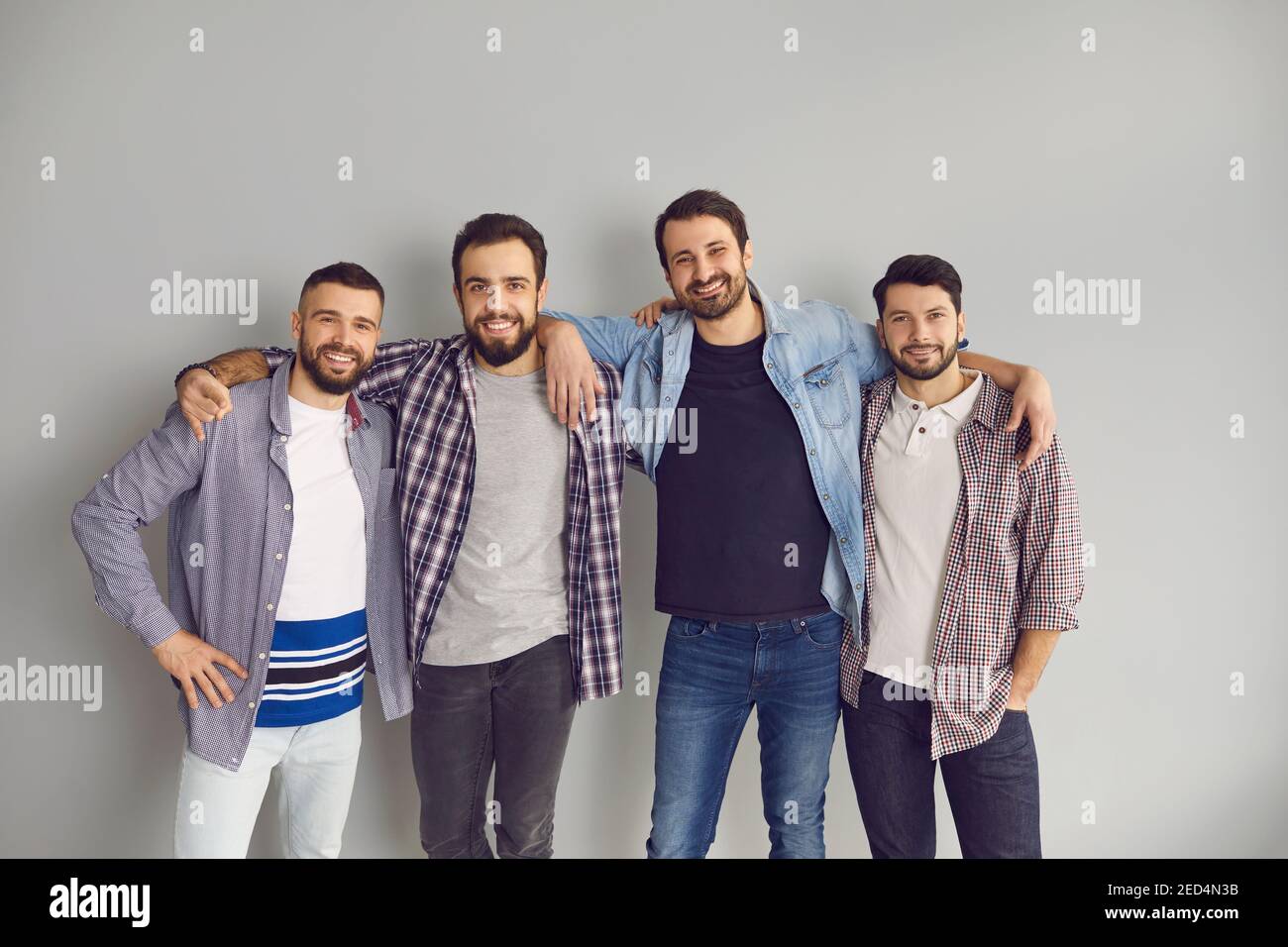 Portrait of happy friends standing with arms around each other's ...