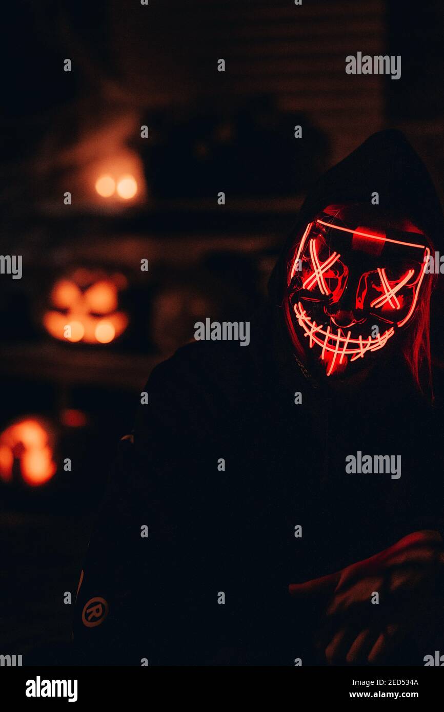 A closeup view of a girl with a red glowing dead mask with a lightsaber ...