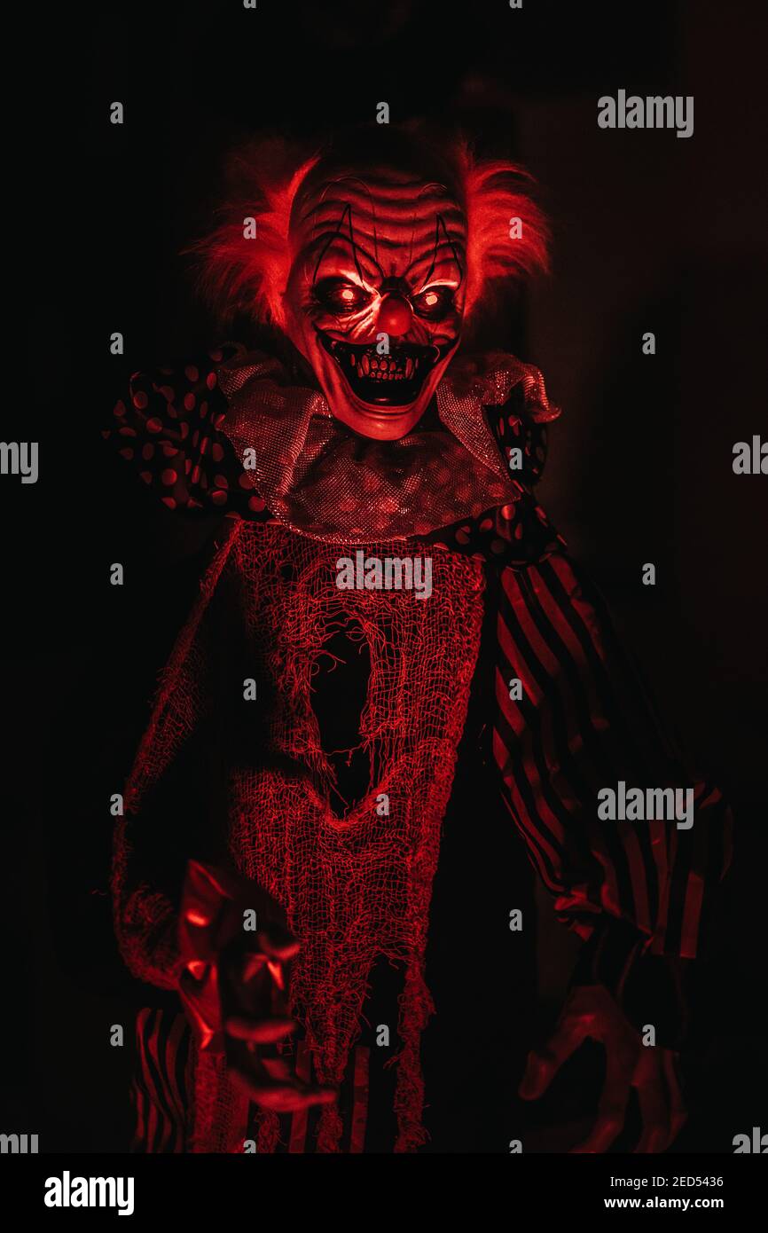A closeup view of a scary clown mannequin placed in the dark room with ...