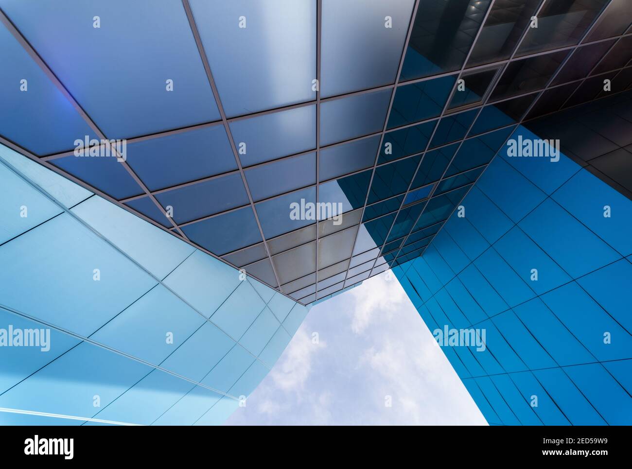 mirrored windows of the facade of an office building with blue panels ...