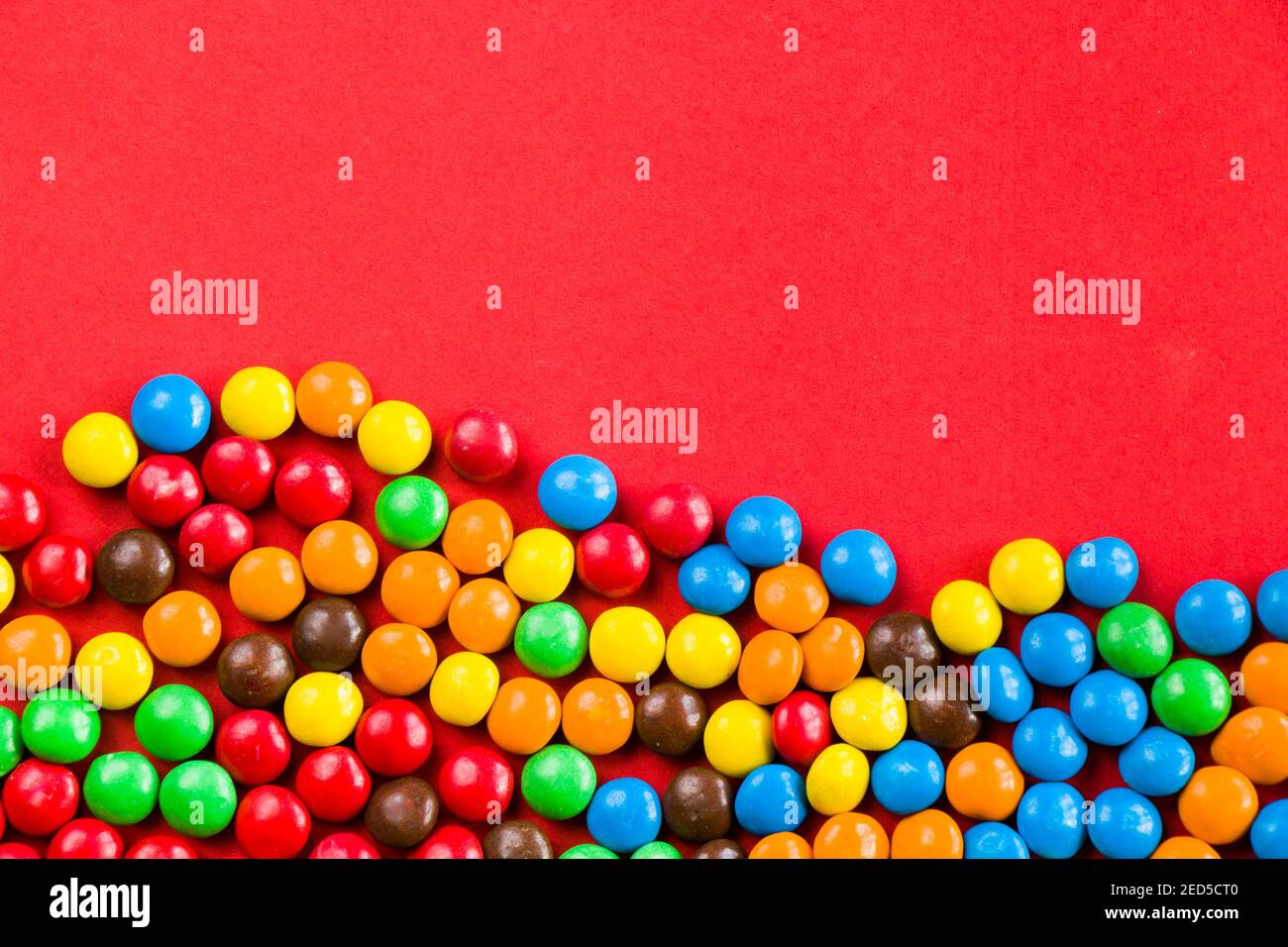 M&M's candy on the red background, colorful candy and multicolored ...