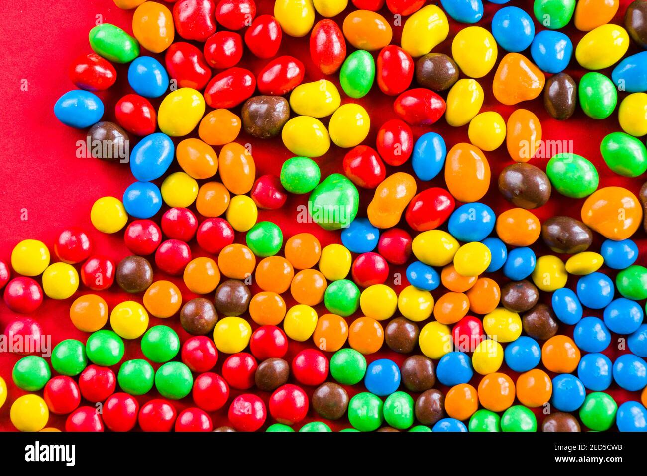 M&M's candy on the red background, colorful candy and multicolored ...