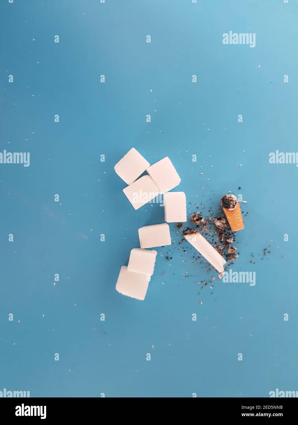 An overhead vertical shot of sugar cubes and a broken cigarette on a ...