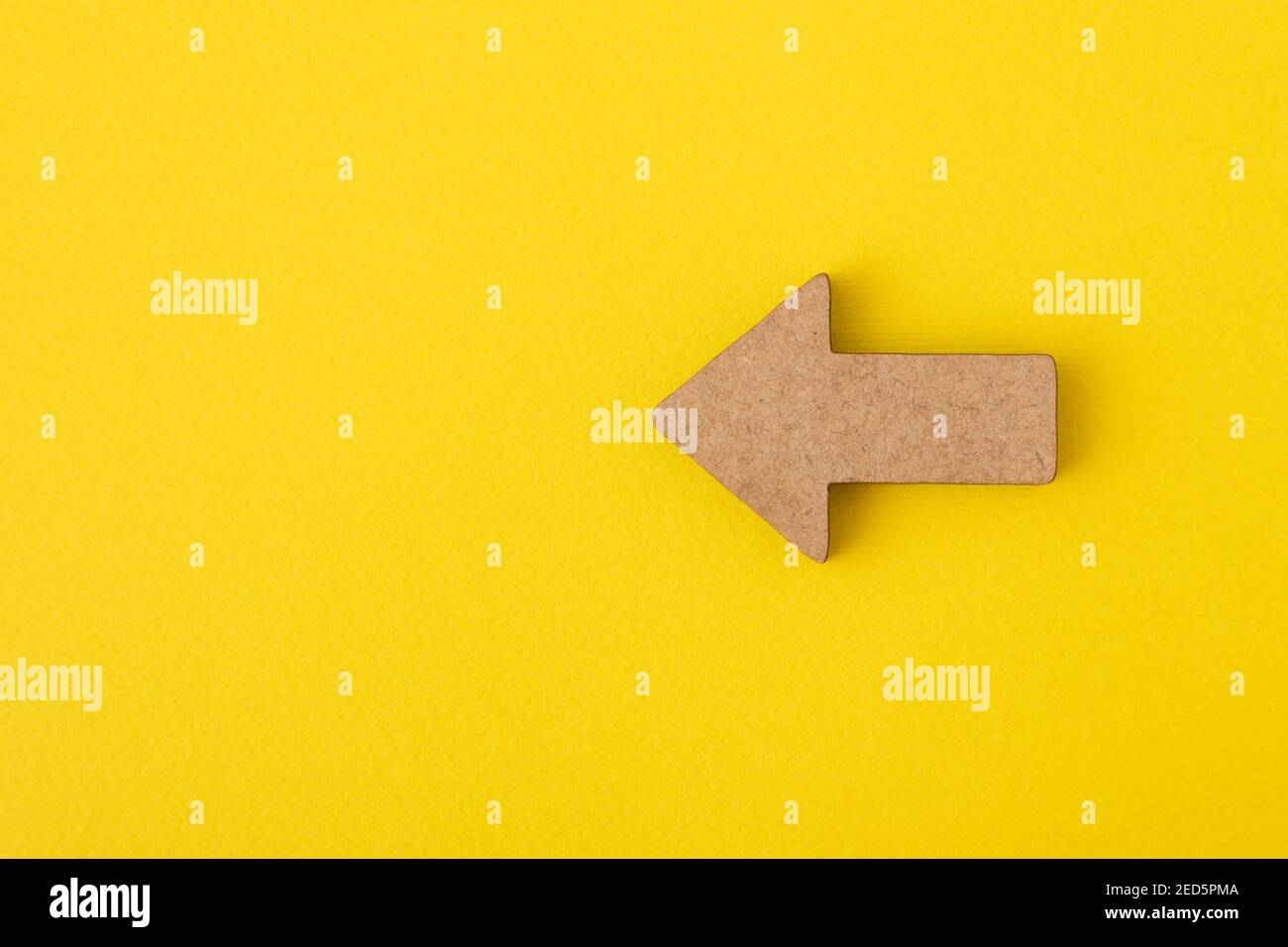 Wooden arrow on yellow background. Direction indicator. Copy space ...