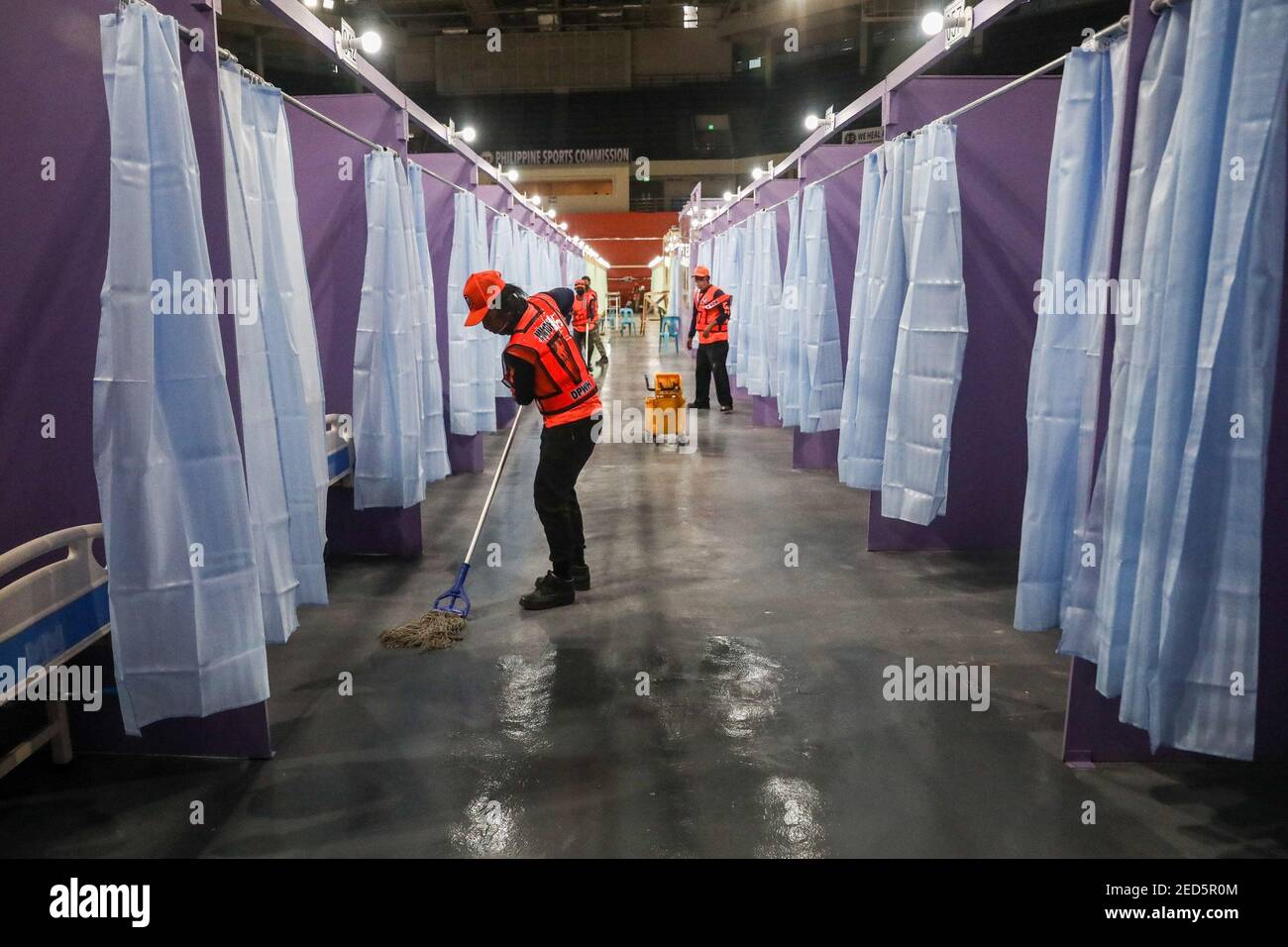 Workers clean cubicles installed inside a sports arena in Pasig City ...