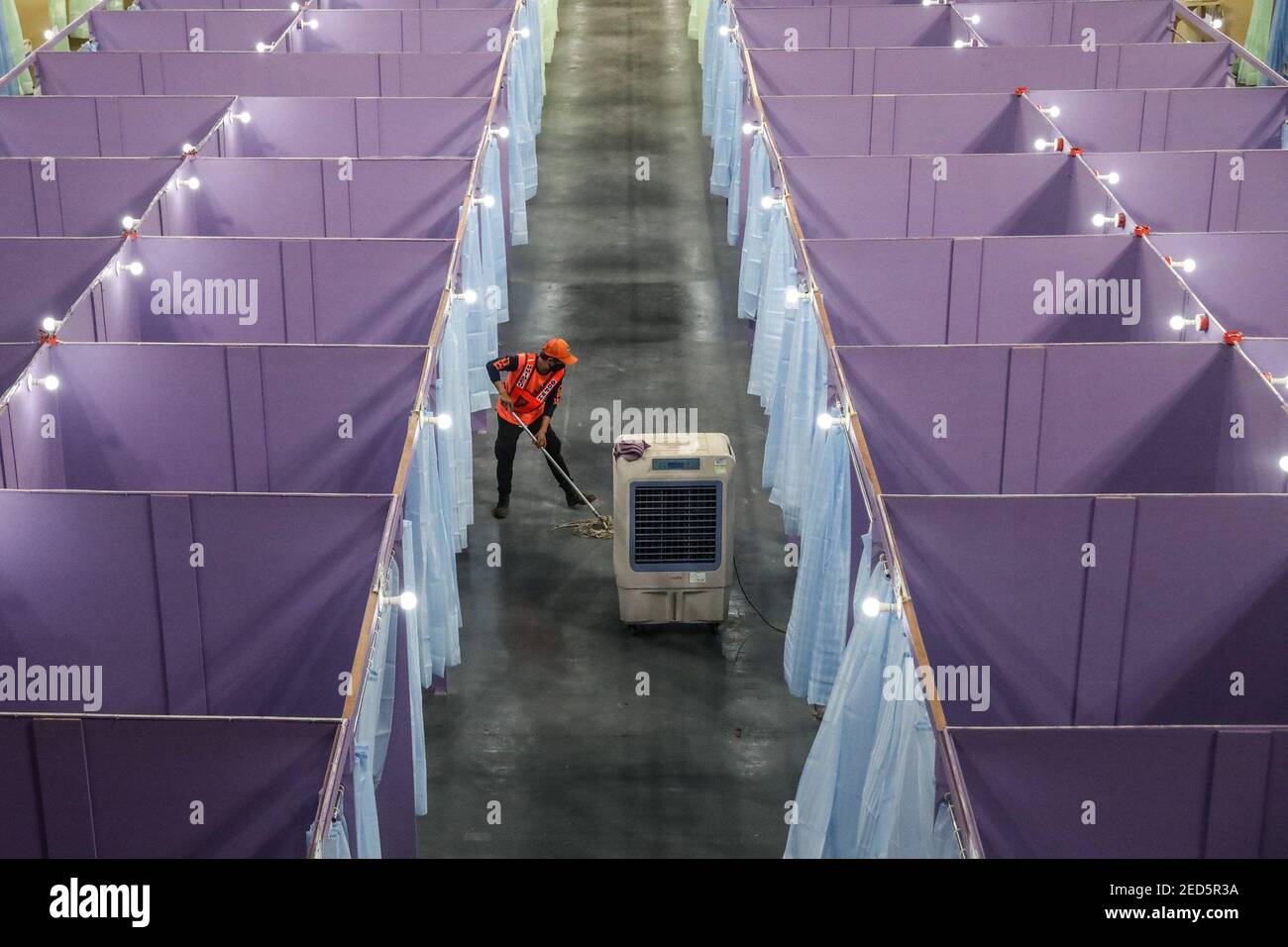 Workers clean cubicles installed inside a sports arena in Pasig City ...