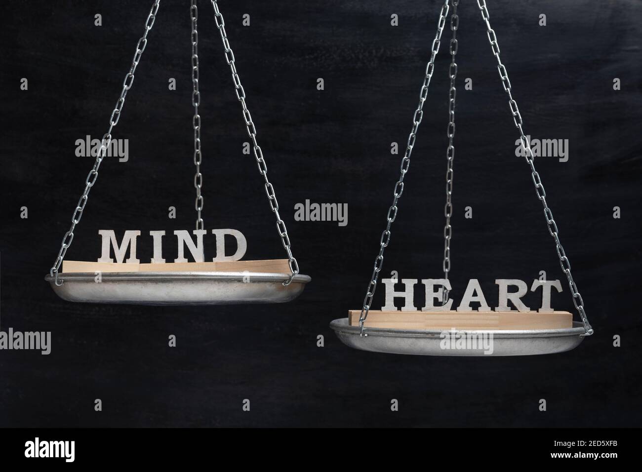 MIND and HEART balance concept. Scales on black background close up ...