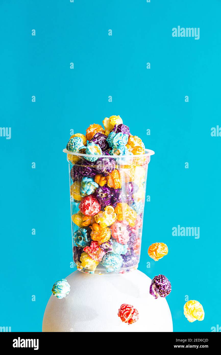 Creative composition with colored popcorn in a transparent glass on a ...