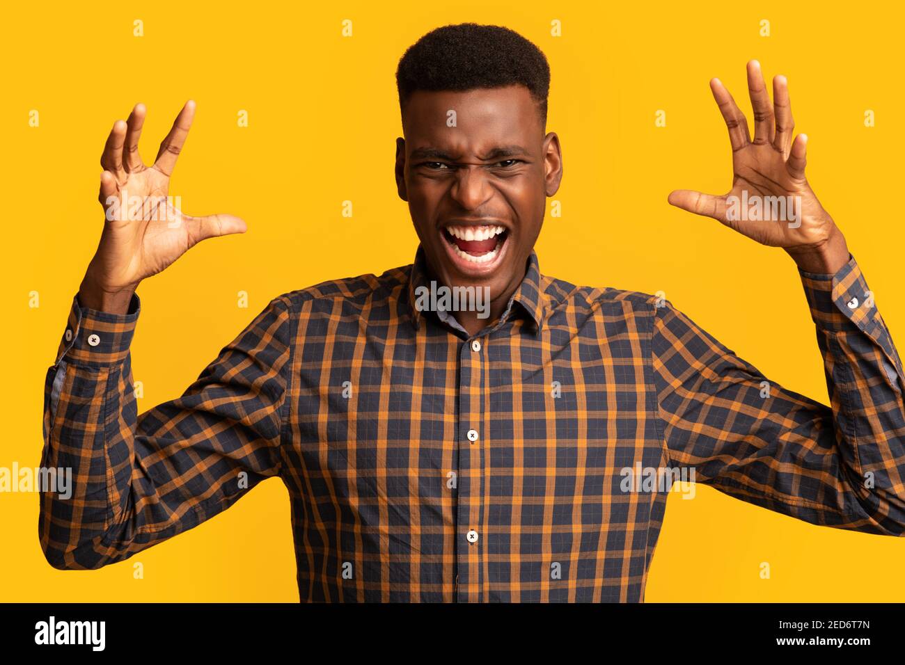 Portrait of young angry black man shouting with rage over yellow ...