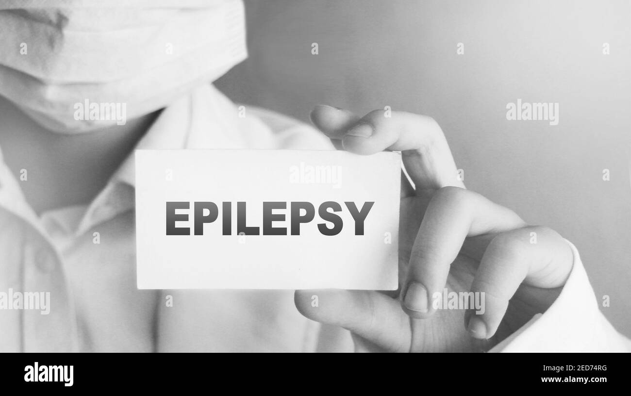 Doctor wearing face mask holding card with diagnosis Epilepsy in his ...