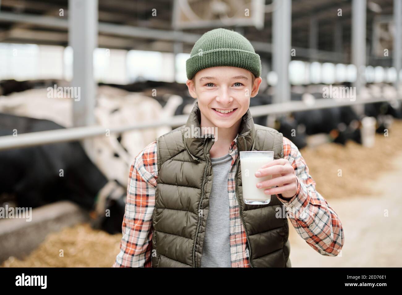 Happy teenage boy with glass of fresh milk looking at you with toothy ...