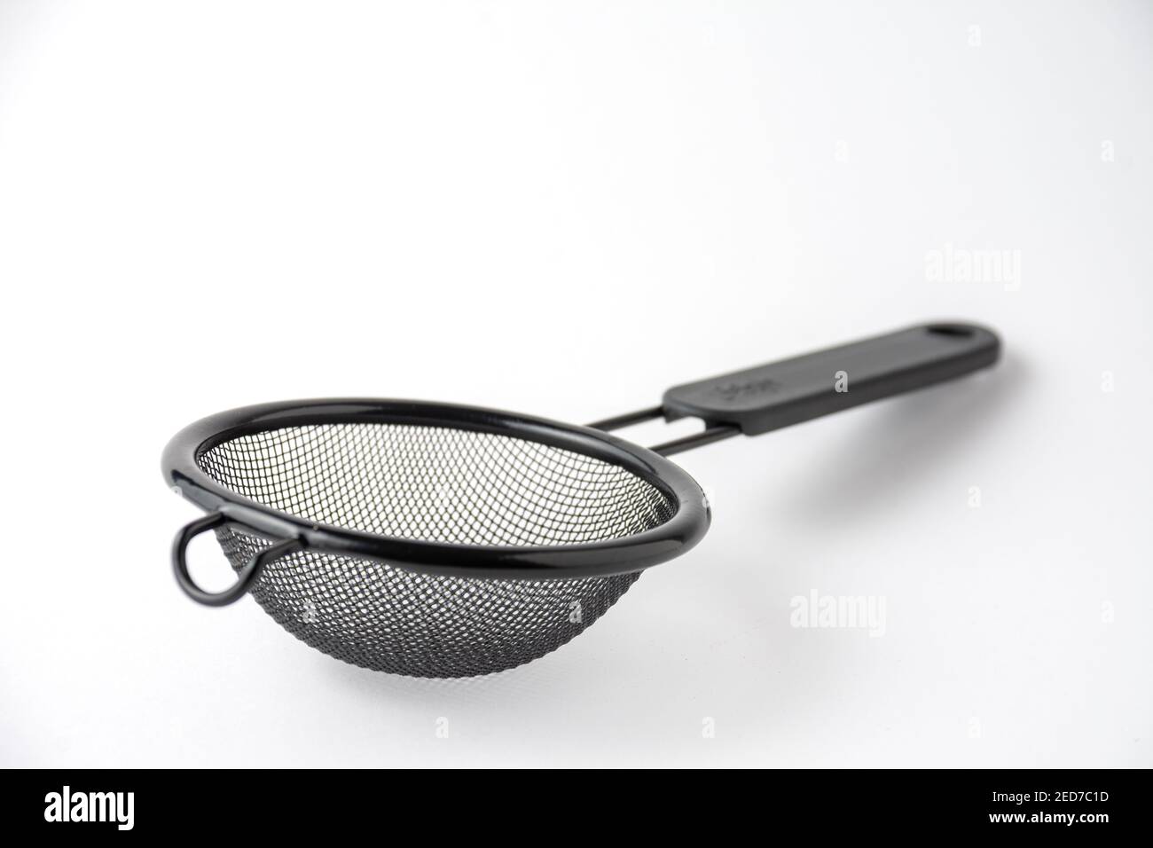 Close-up of black metal strainer, on white background, horizontal, with ...