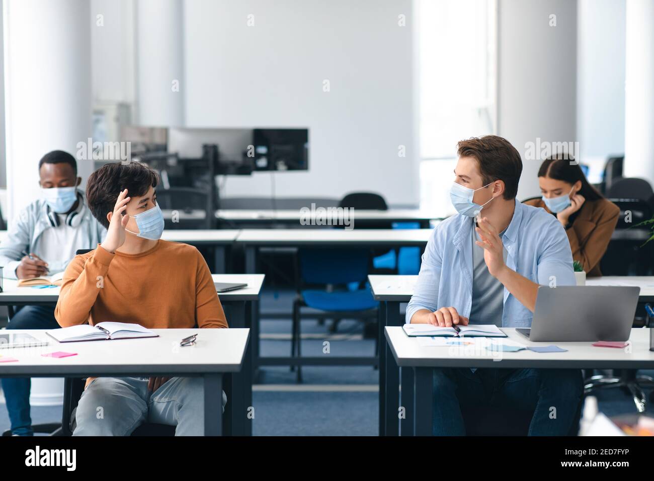 Diverse students wearing face masks greeting and waving Stock Photo - Alamy