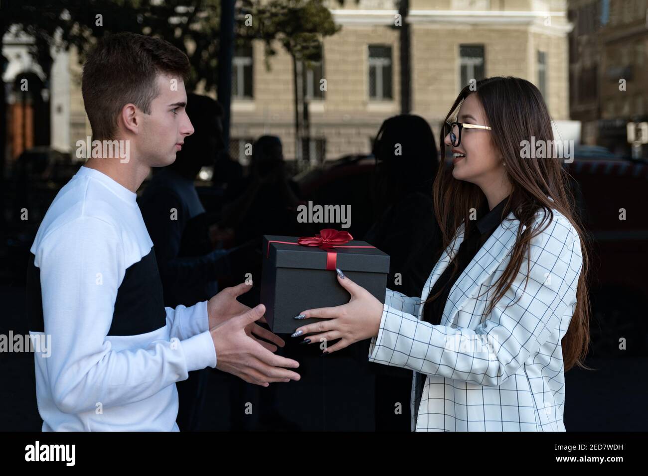 Young woman gives gift to lover. Girl gives present to friend Stock ...