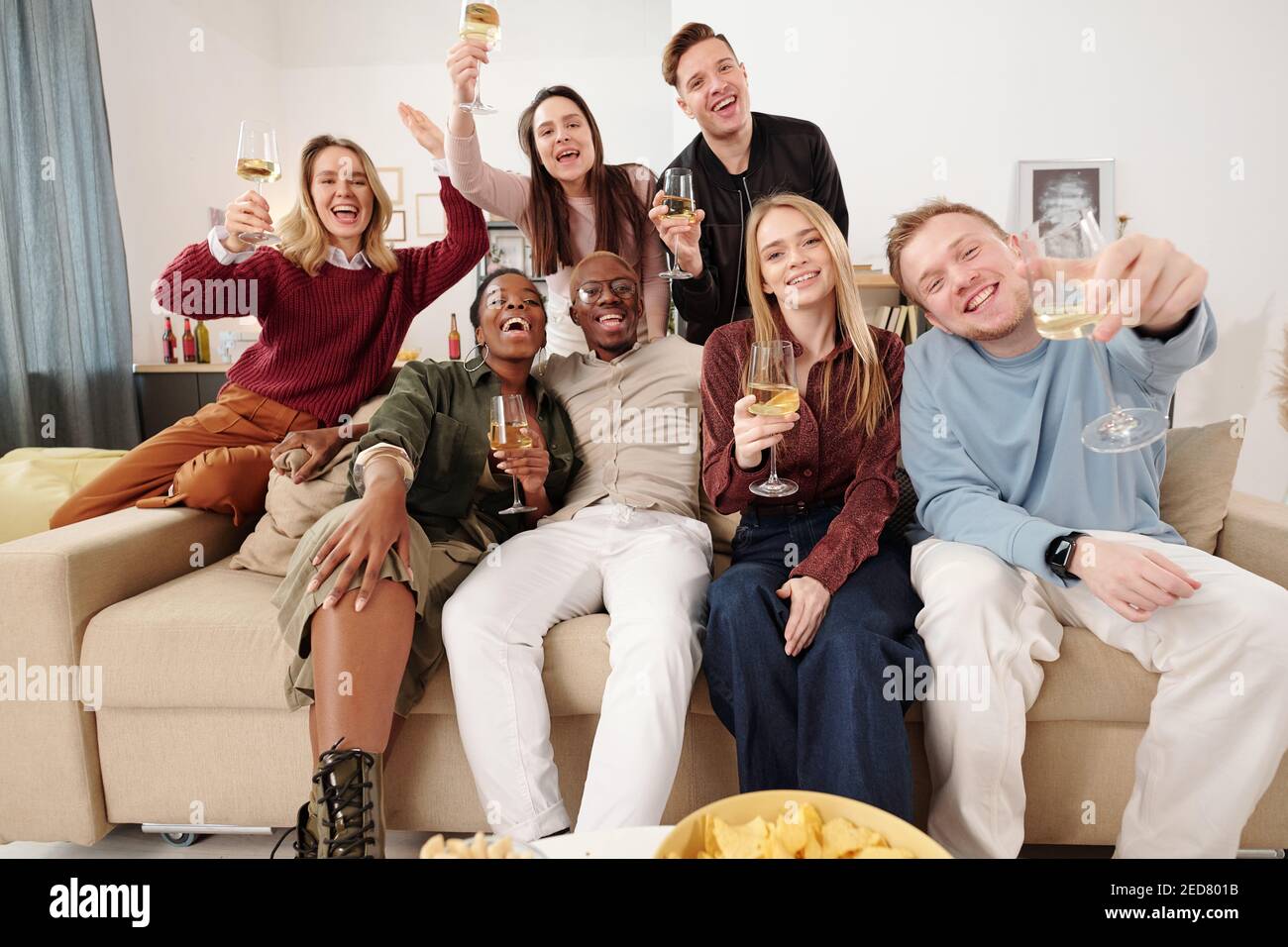 Group of young joyful intercultural friends in smart casualwear sitting ...