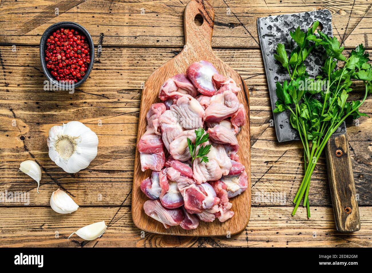 Raw uncooked chicken gizzards, stomach on a cutting board. wooden ...