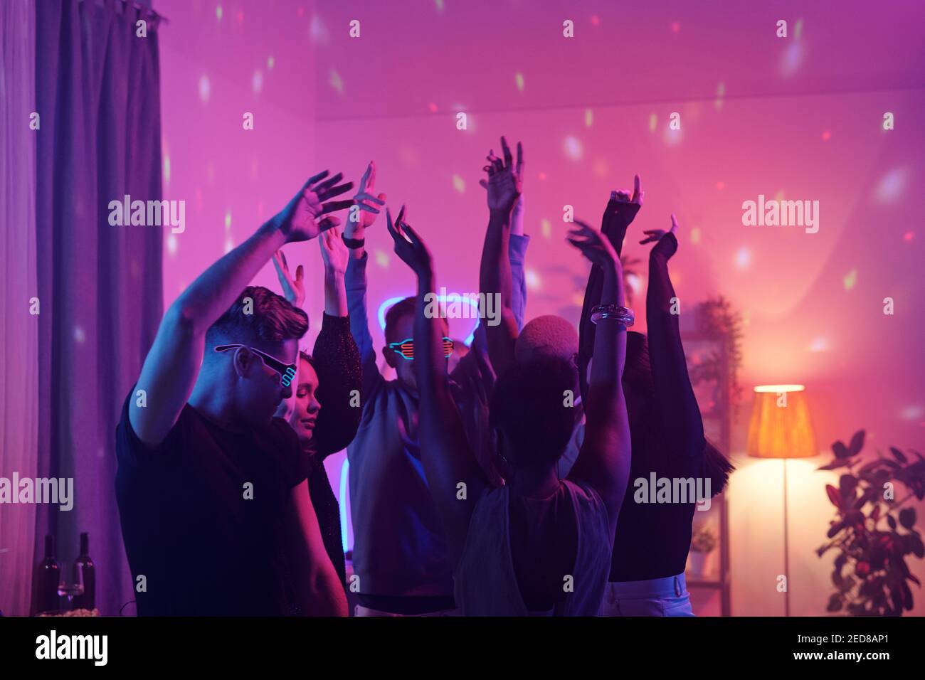Young intercultural friends in smart casualwear raising arms while ...