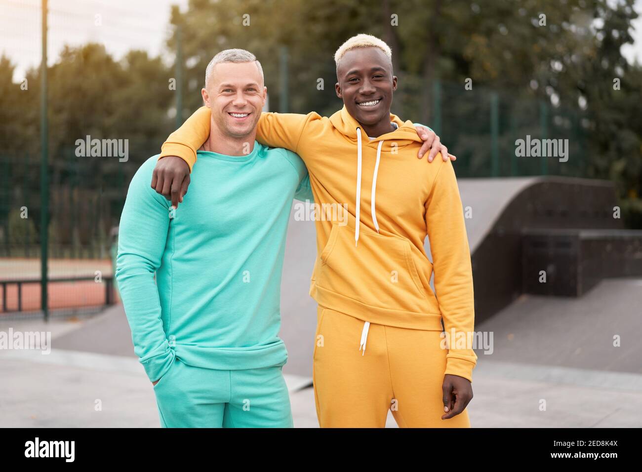 International friendship. Two happy diverse men in bright sportsuits ...