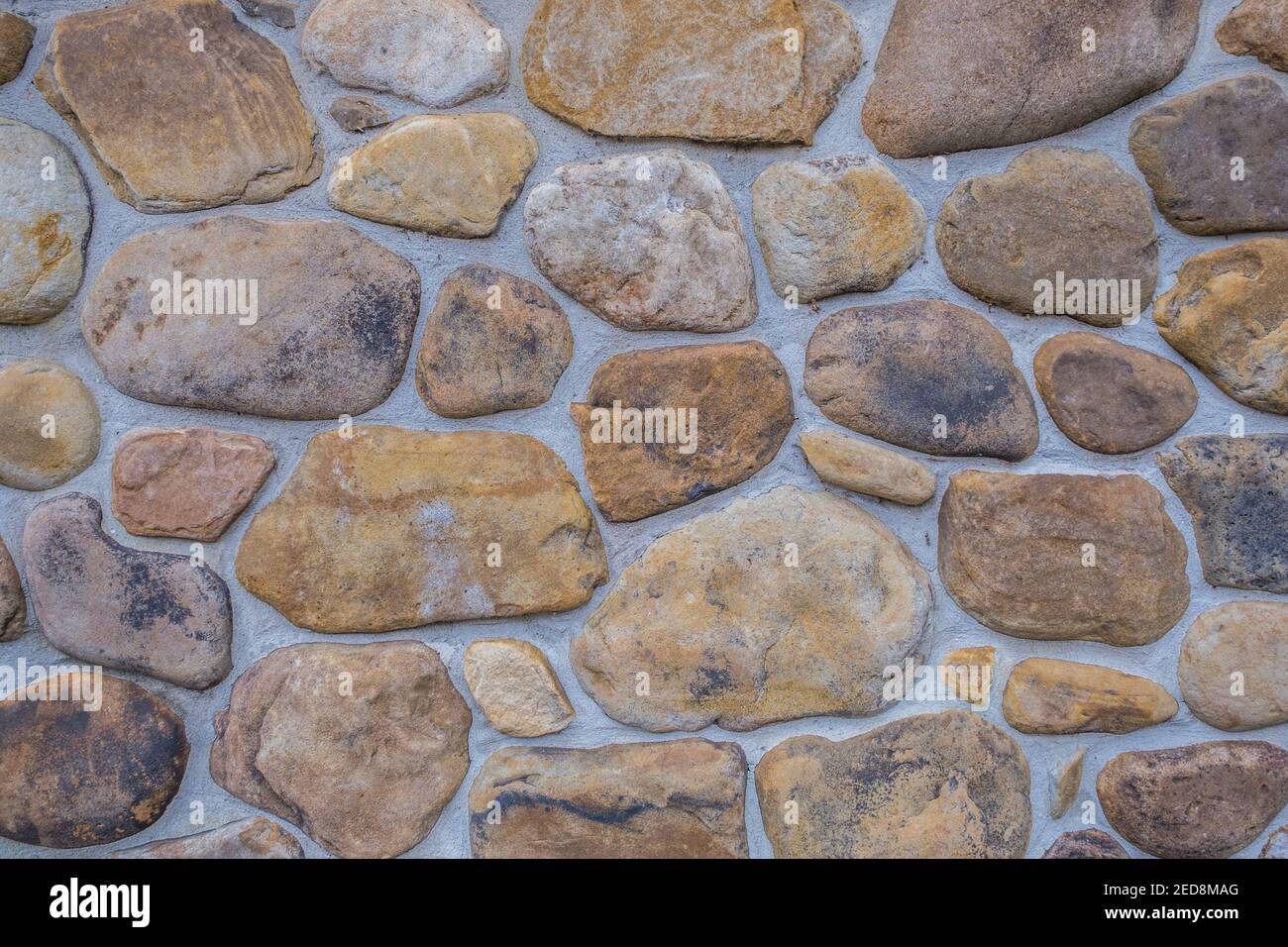 Variety of river rocks made into a stone wall on a building surrounded ...