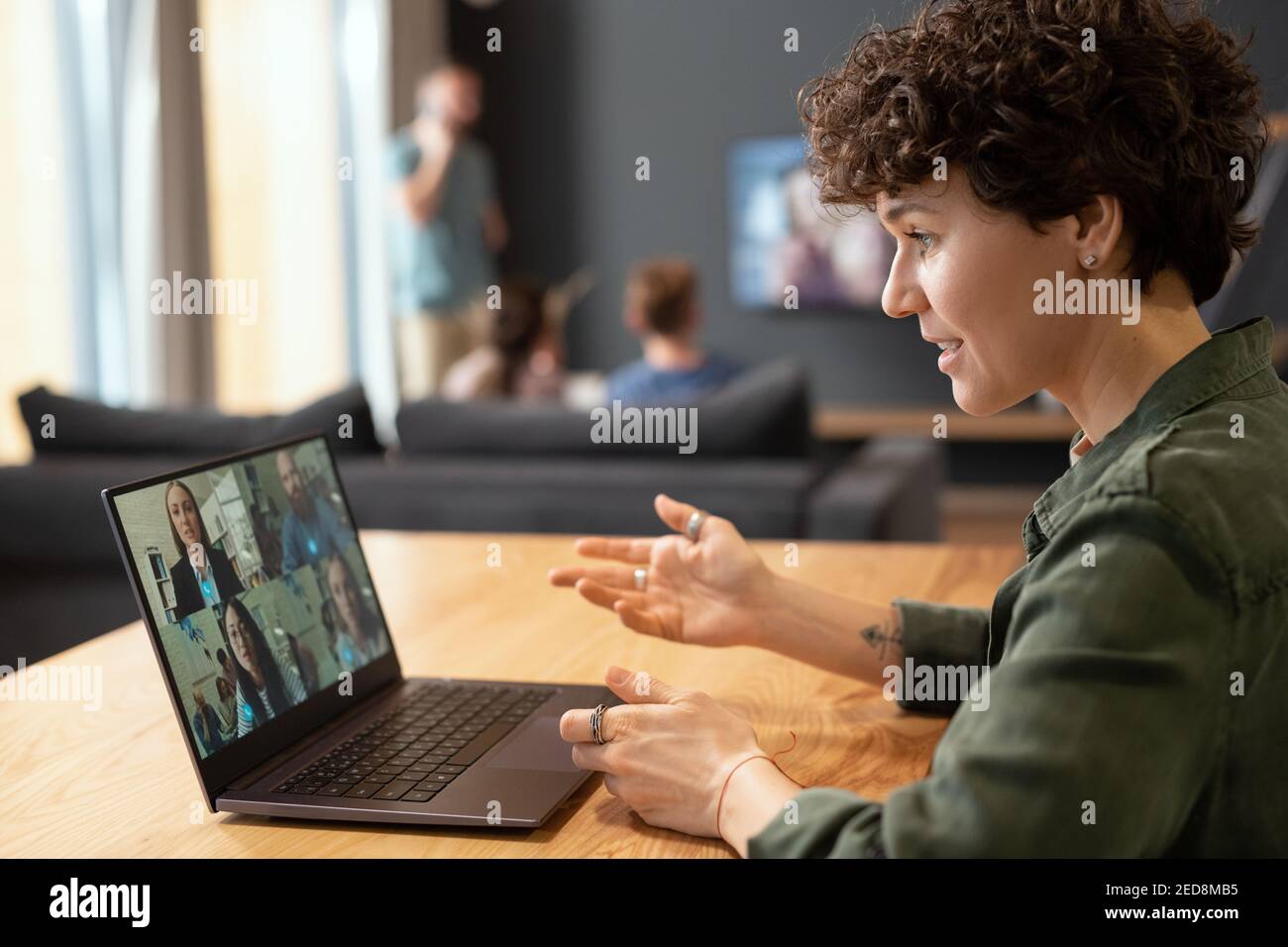 Side view of young contemporary businesswoman sitting by table in front ...