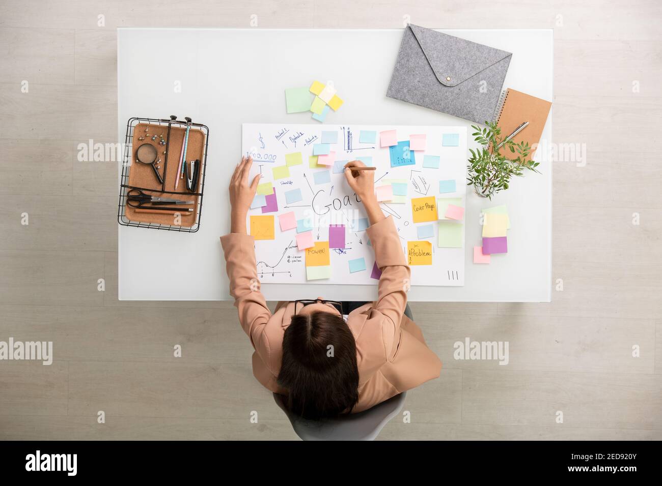 Overview of young elegant businesswoman making working notes while ...