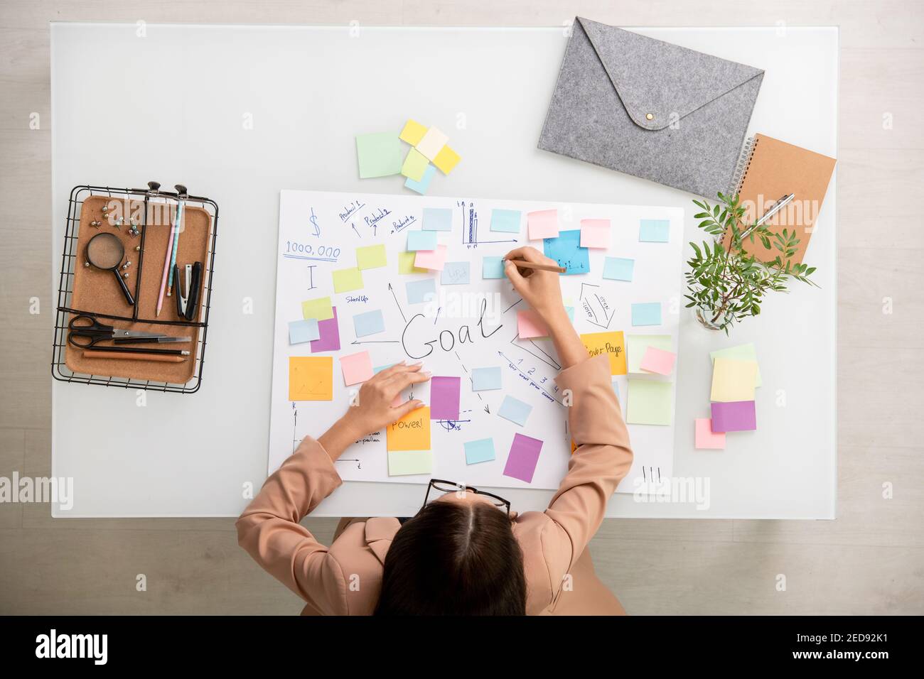 Overview of brunette businesswoman making working notes while bending ...