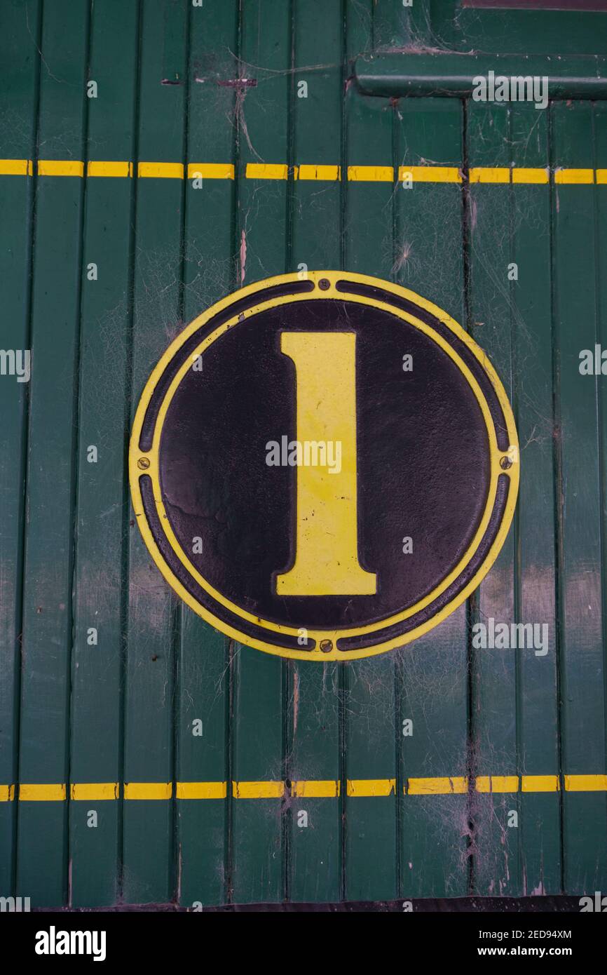 Old-world number 1 in yellow circle on dark green timber background ...